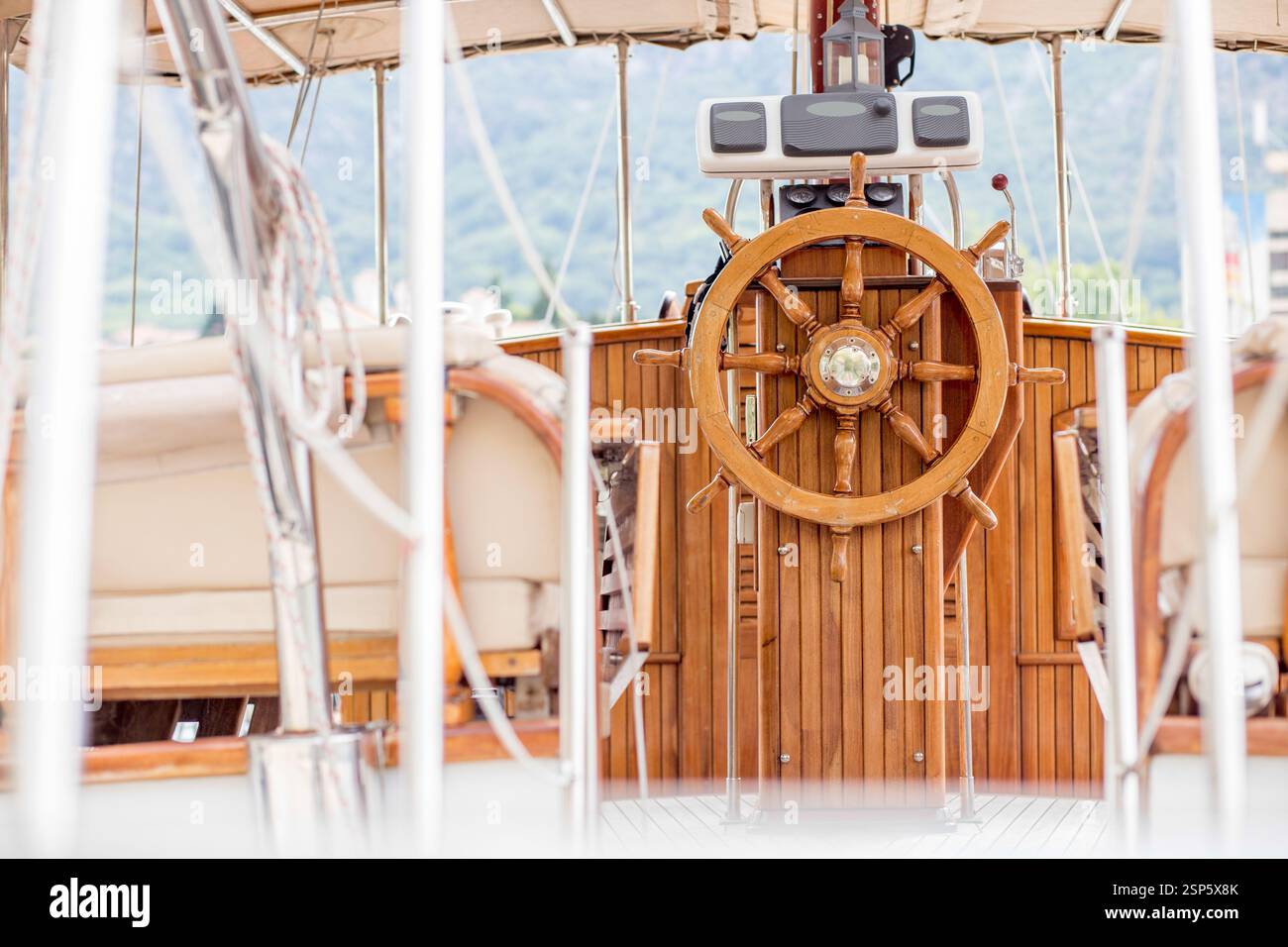 Wooden ships wheel mounted on a polished wooden console in the yachts ...