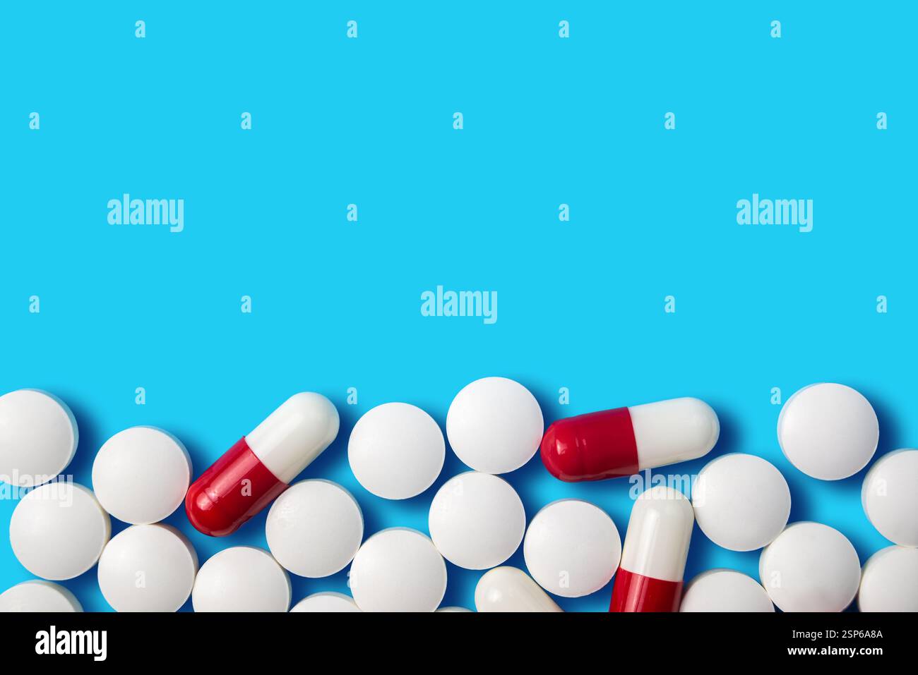 Different shapes and colors of capsules and tablets are spread across a ...