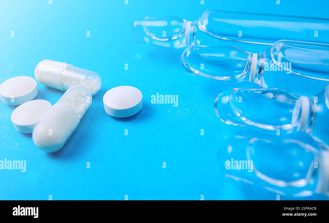 Various capsules, tablets, and glass ampoules are neatly placed against ...