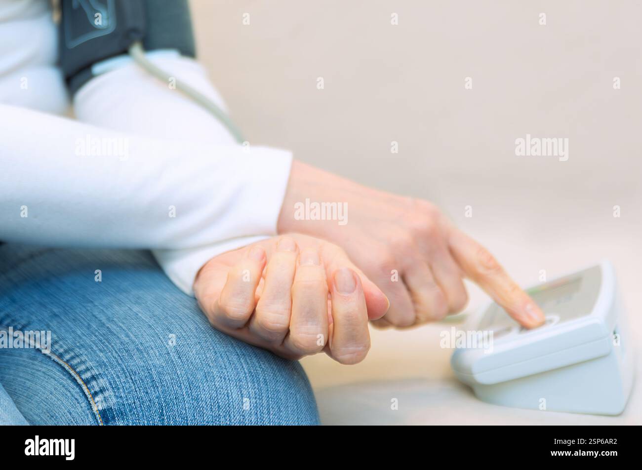 A person measures their blood pressure with a monitor while seated ...