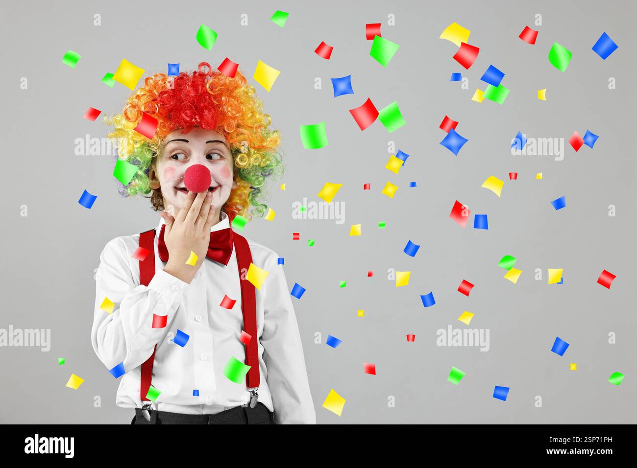 Cute boy dressed like clown under falling confetti on grey background ...