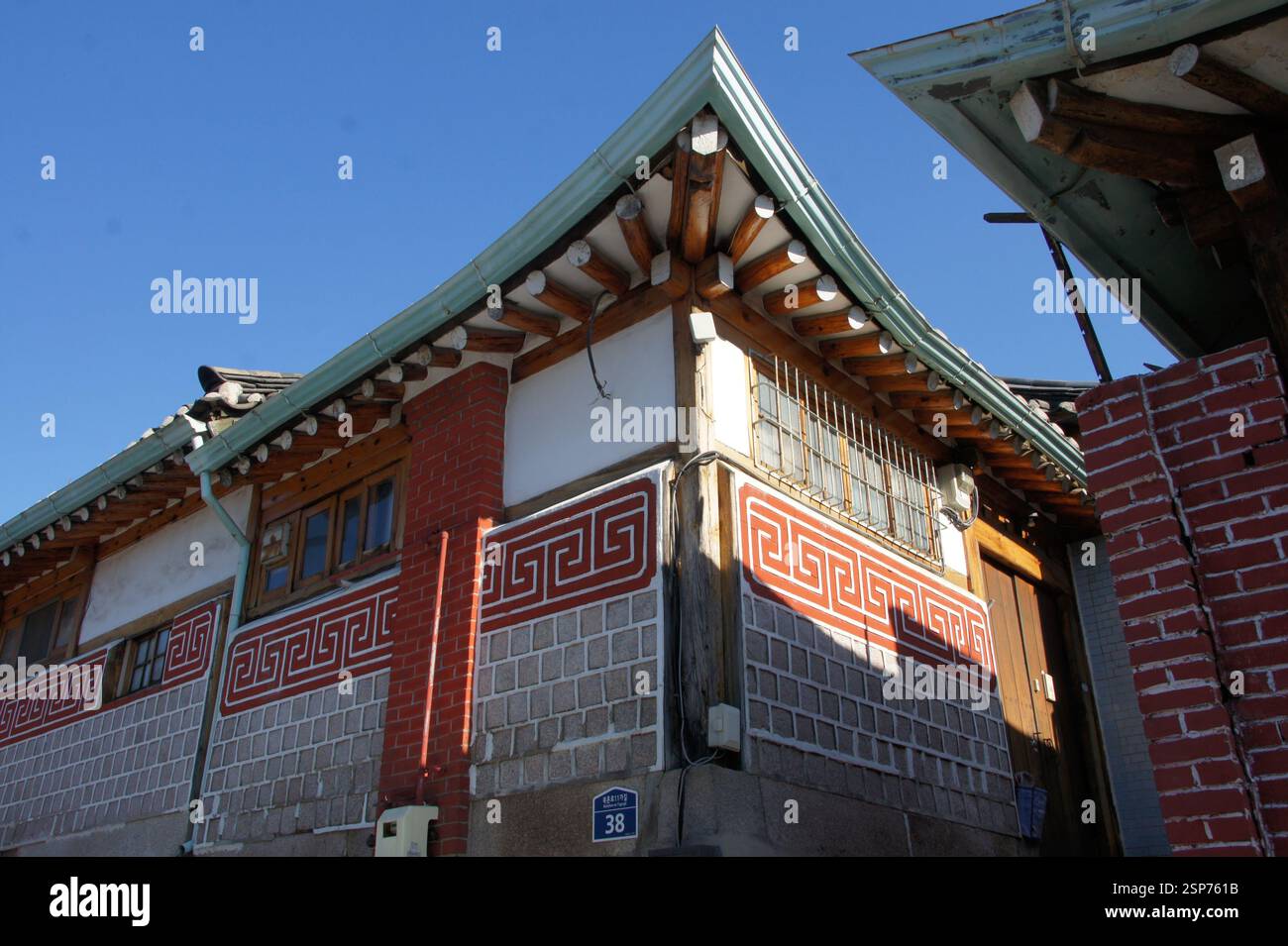 Korean traditional house with red brick walls and tiled roof. Geometric patterns decorate the ...