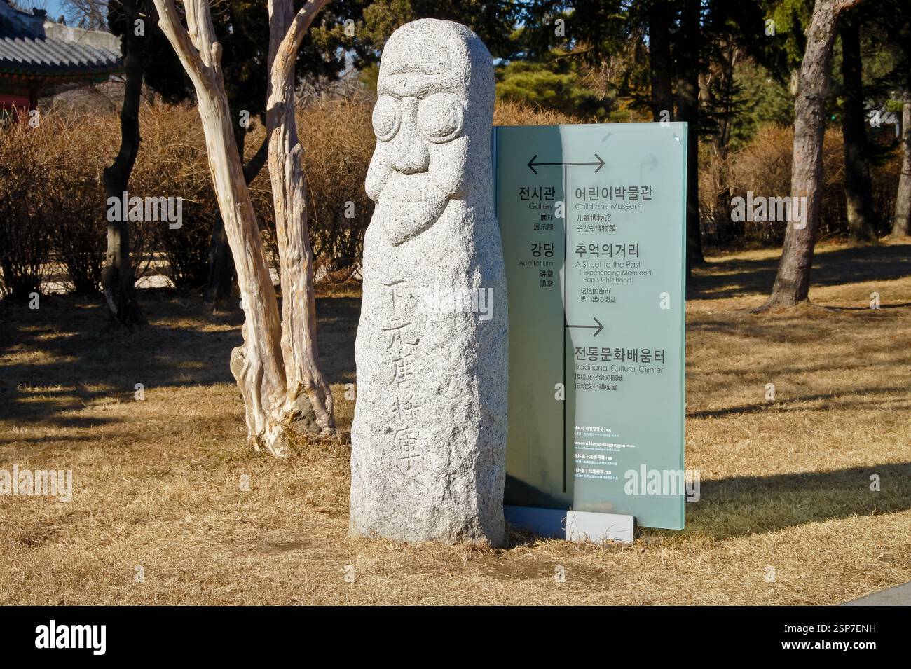 Korean statue with weathered face and inscription, flanked by modern ...