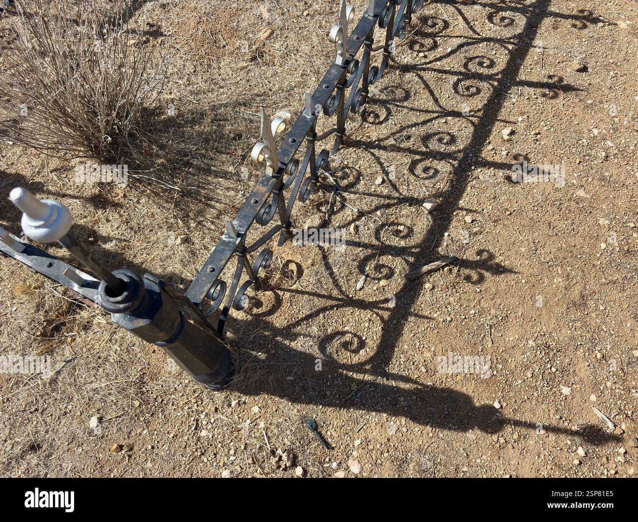 Ornate wrought iron fence casting shadows on dry ground Stock Photo - Alamy