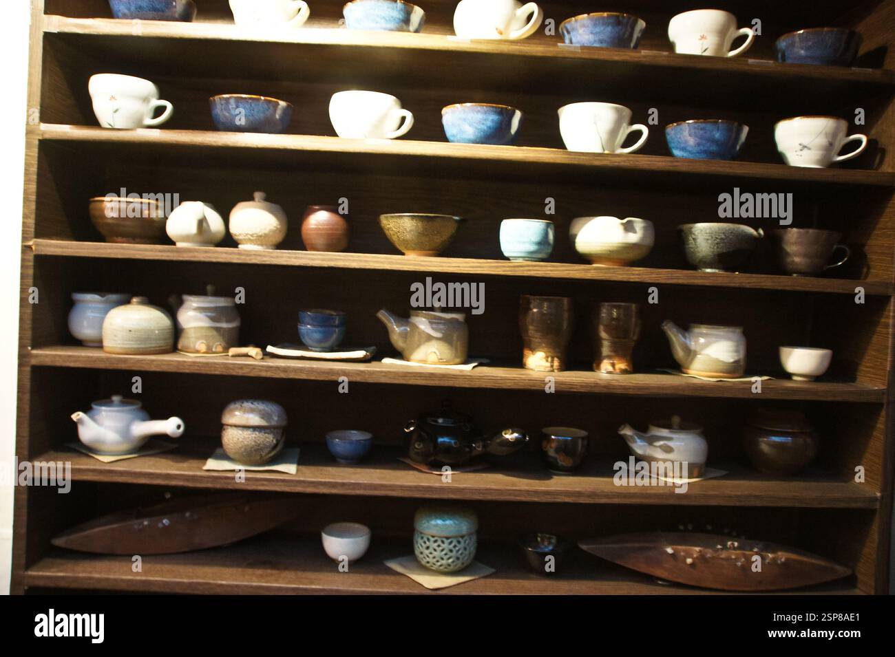 Shelves overflowing with pottery. Cups, bowls, and teapots in various ...