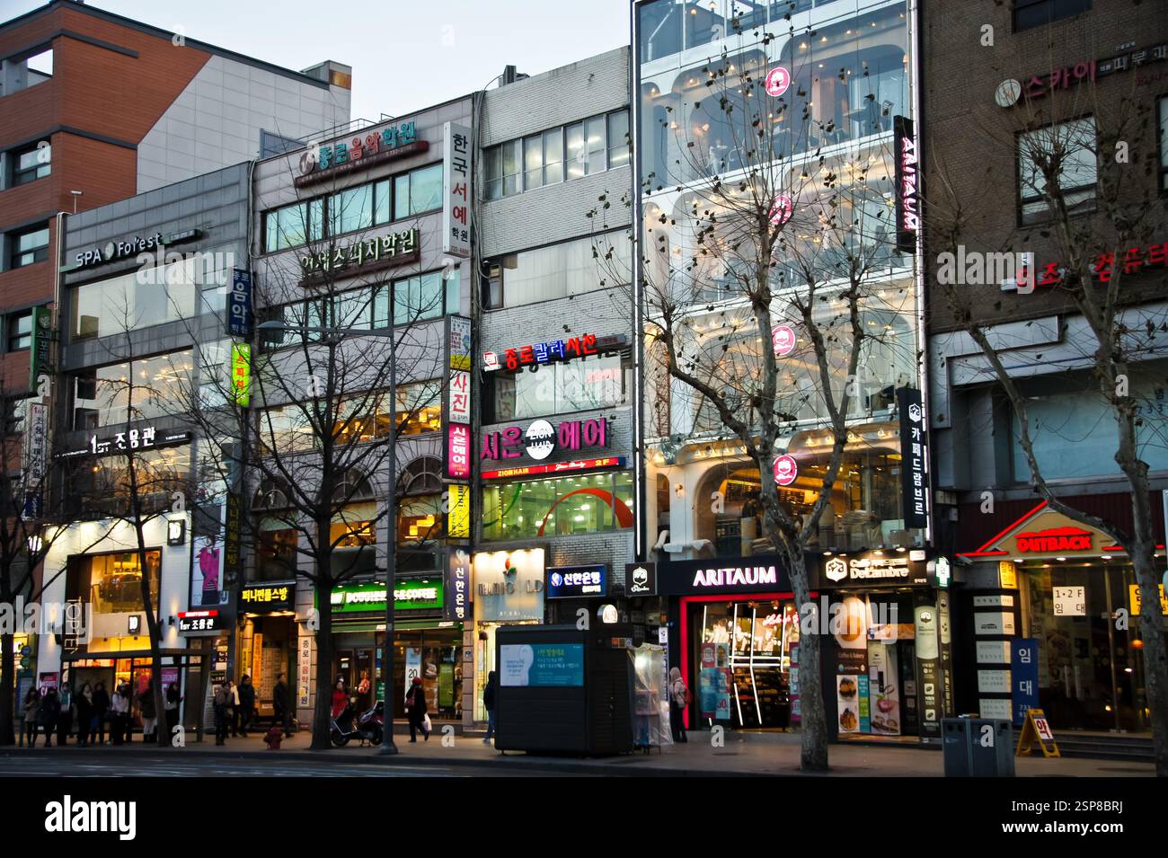 Korean street at night. Neon signs illuminate storefronts. Pedestrians ...