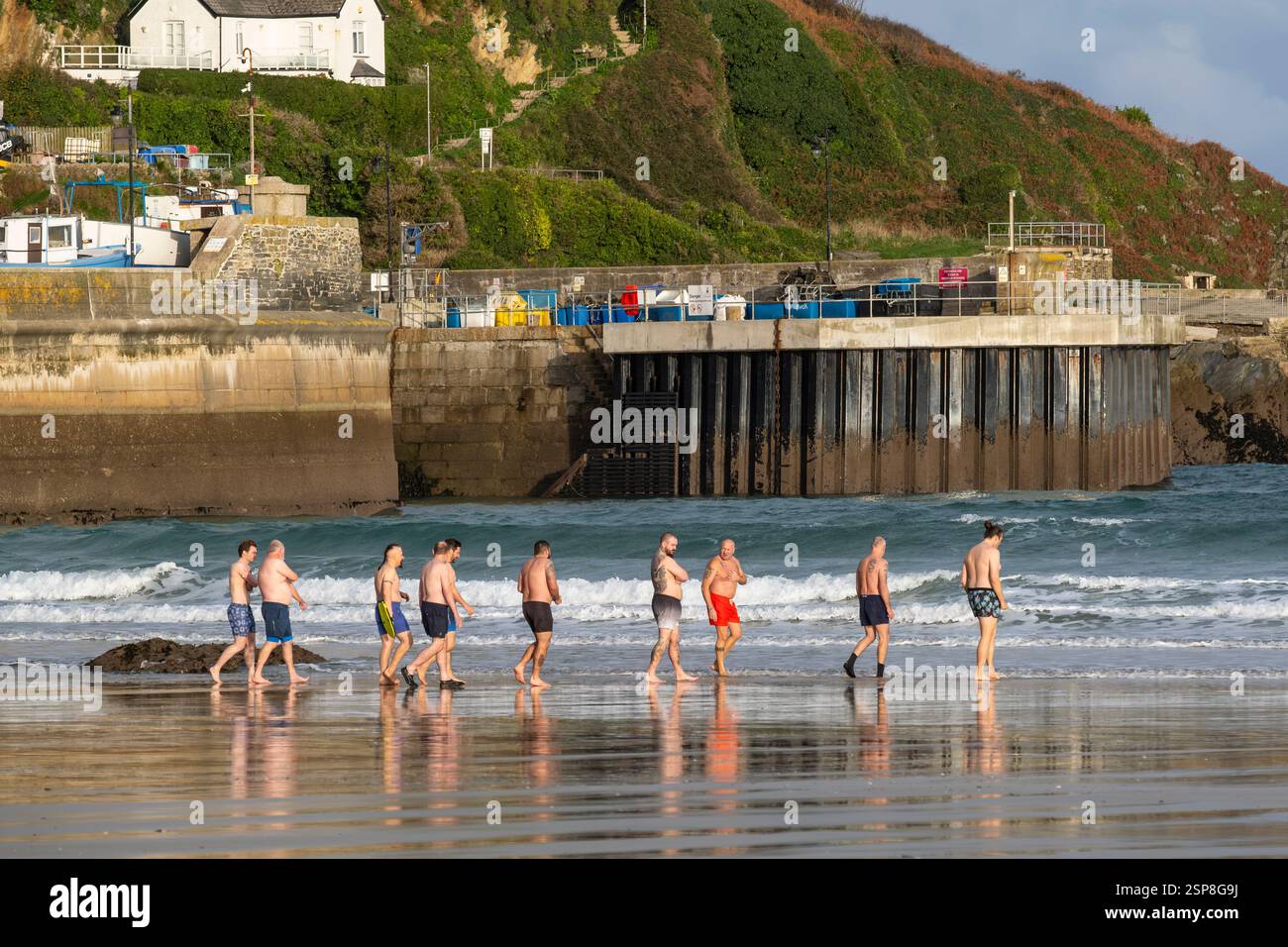 A group of male cold water swimmers walking into the sea for an early ...