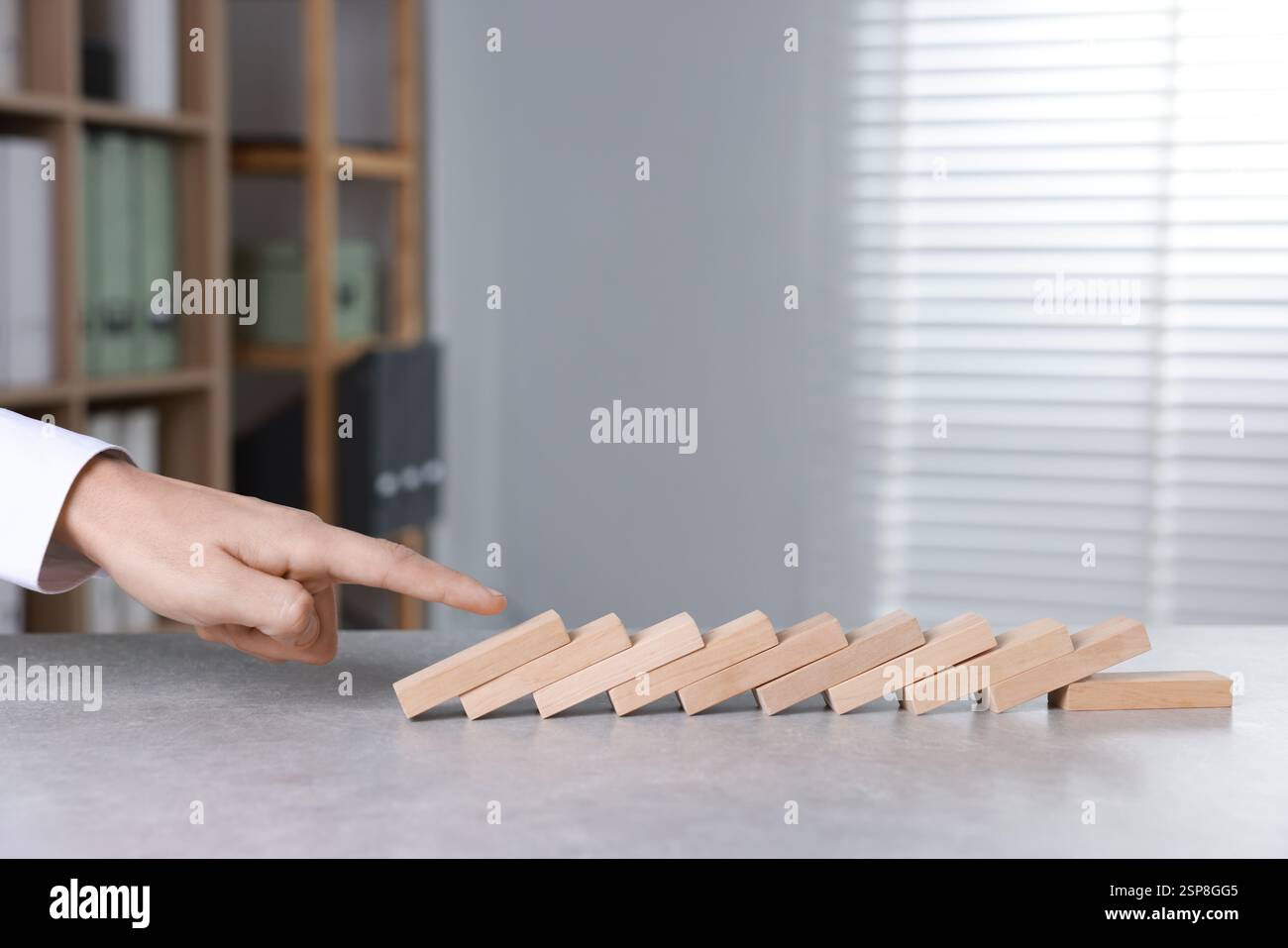 Domino effect. Man pushing wooden blocks at table, closeup Stock Photo ...