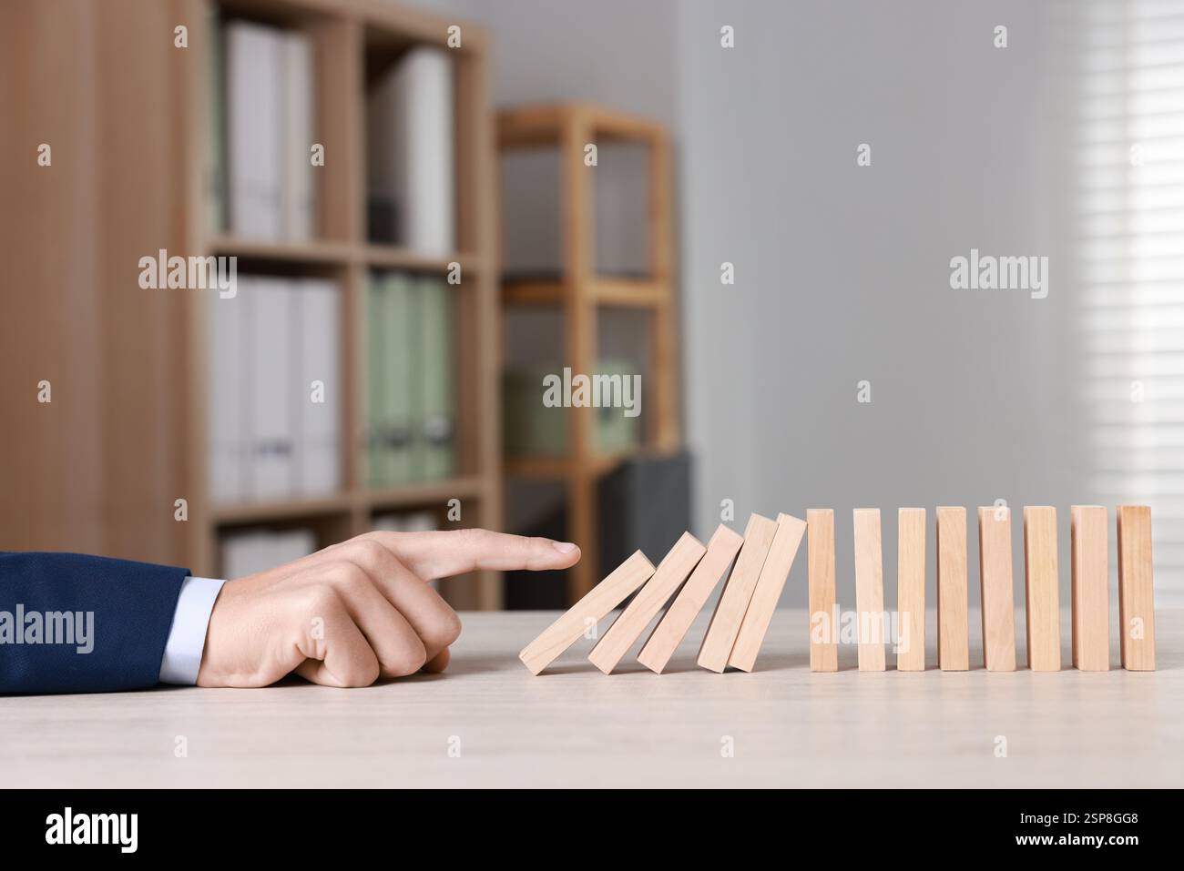 Domino effect. Man pushing wooden blocks at table, closeup Stock Photo ...