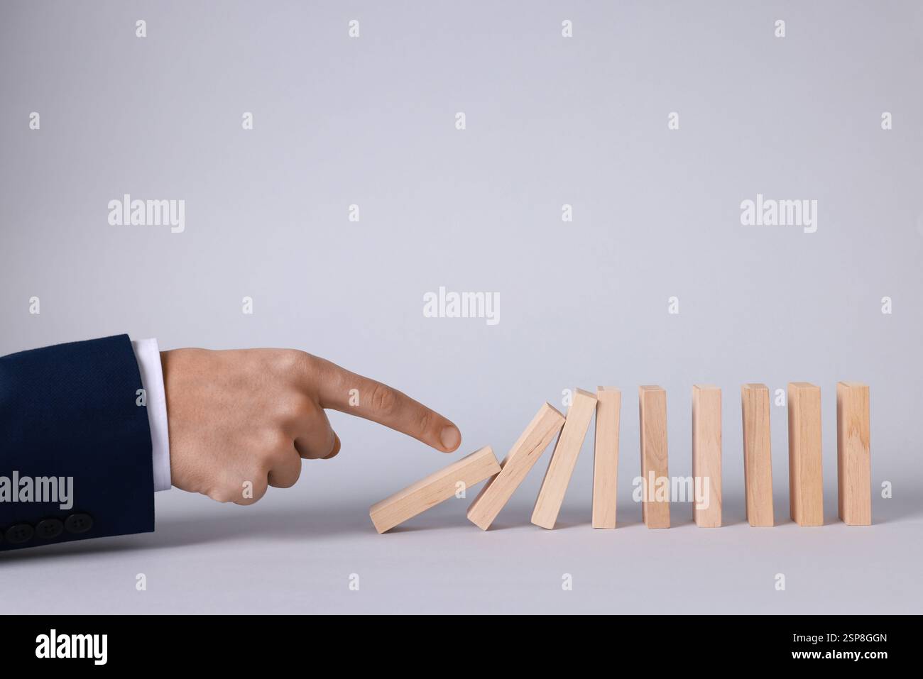 Domino effect. Man pushing wooden blocks on light background, closeup ...