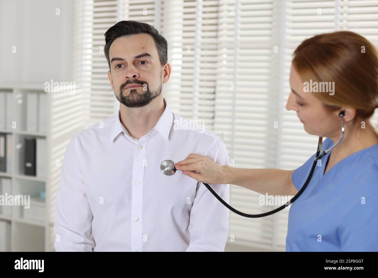 Cardiologist with stethoscope listening patient's heartbeat in hospital ...