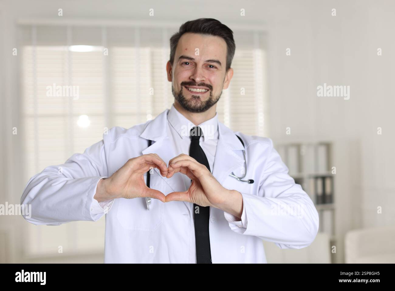 Smiling cardiologist making heart with hands in clinic Stock Photo - Alamy