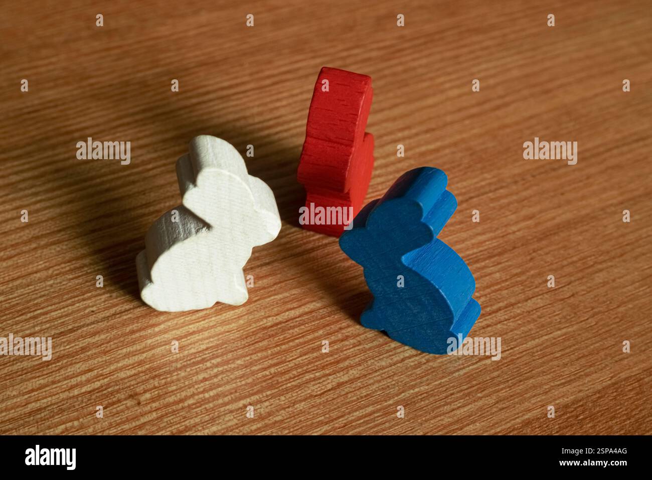 White, red and blue rabbits face to face on a brown wooden table using ...