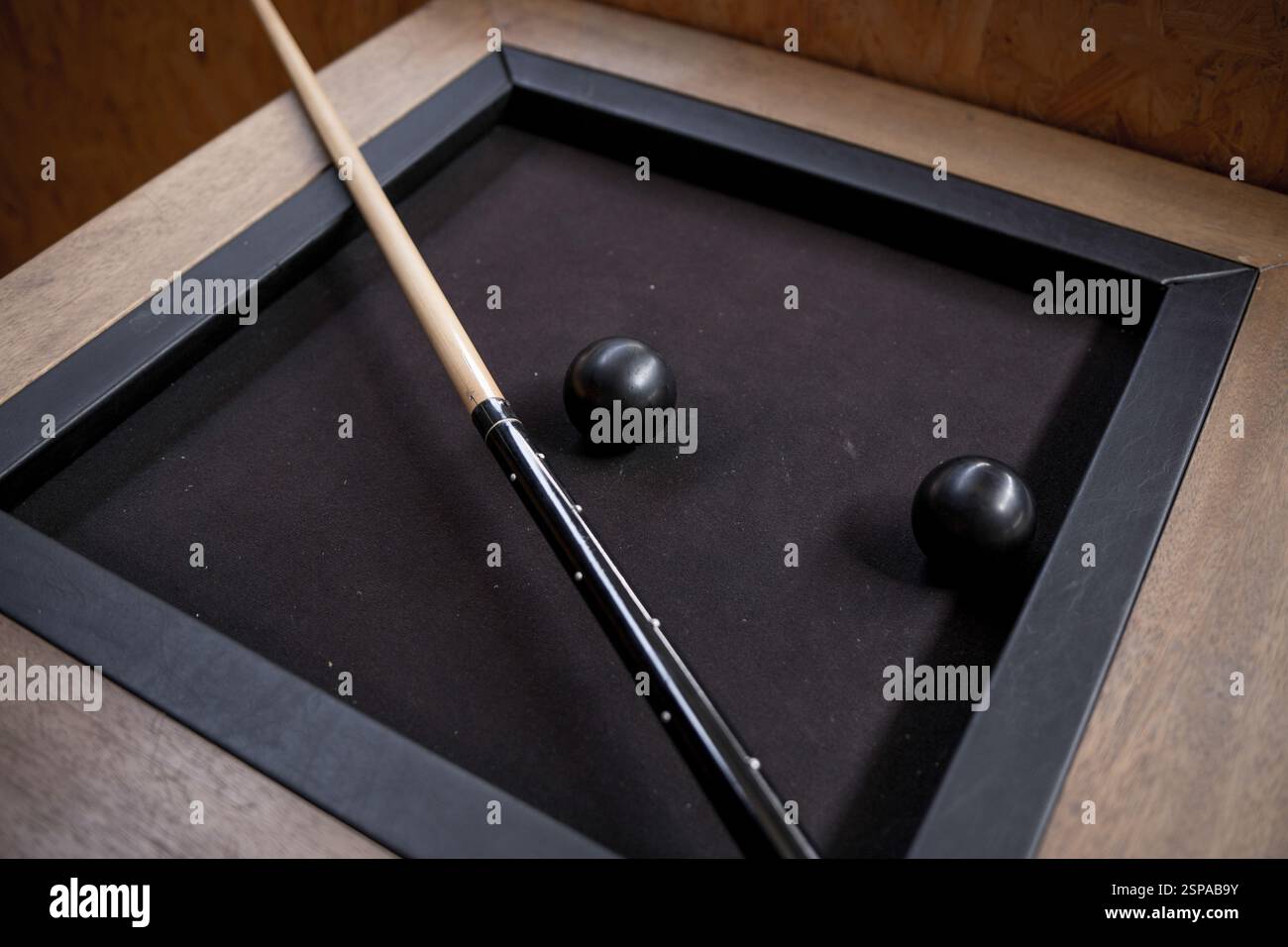 Black square pool table surface with two black balls and a cue stick ...