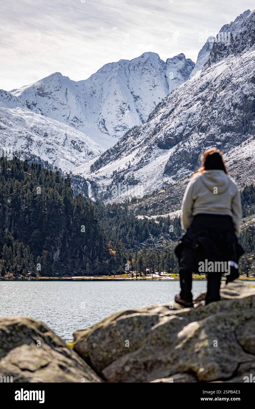 A female hiker wearing a light gray hoodie and black pants stands on ...