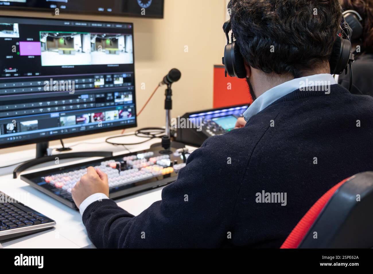 A television director in a broadcast control room, actively guiding a ...
