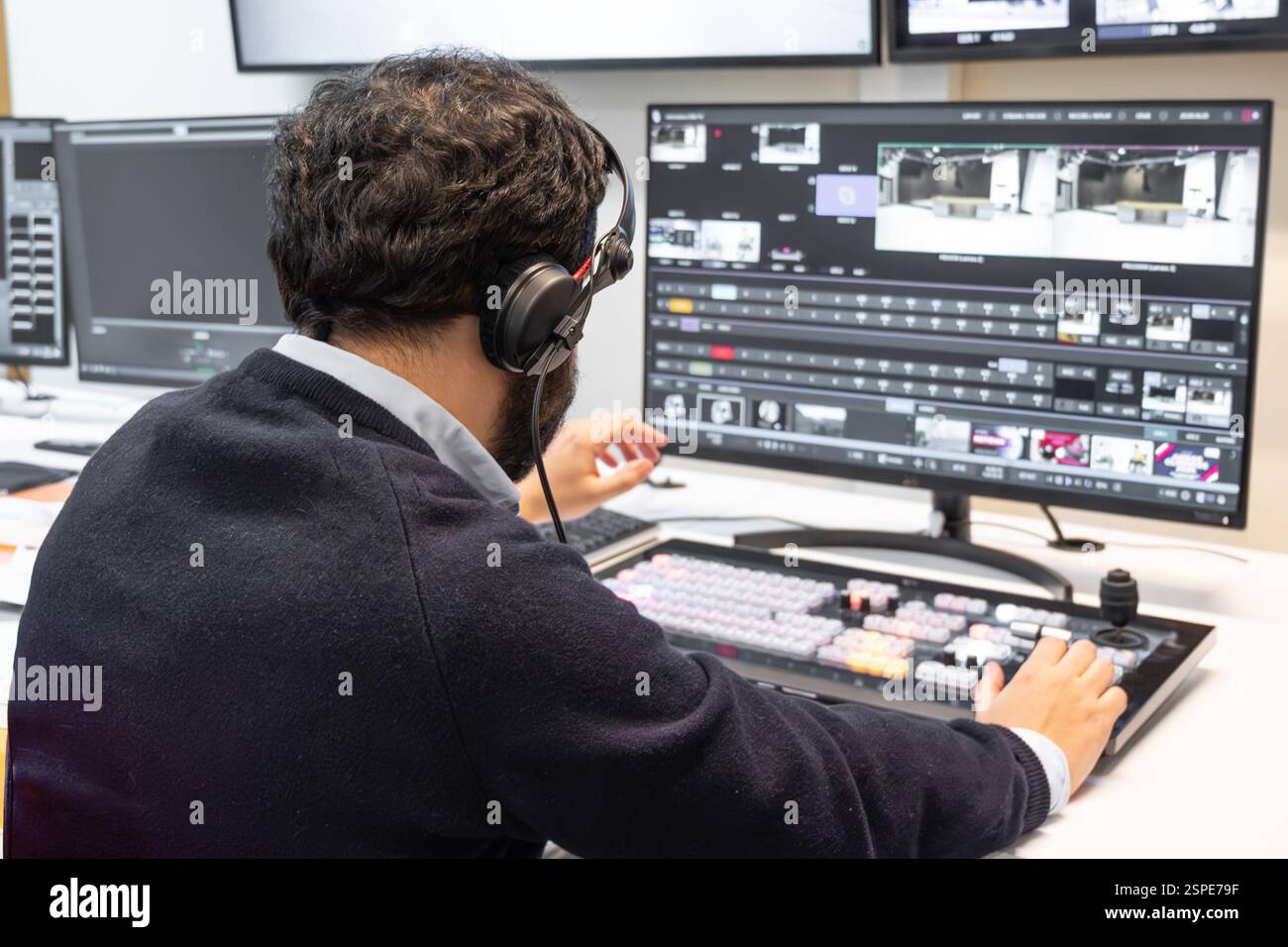 A television director in a broadcast control room, actively guiding a ...