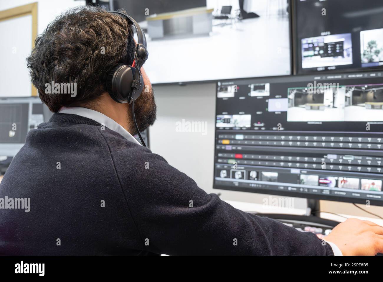 A television director in a broadcast control room, actively guiding a ...