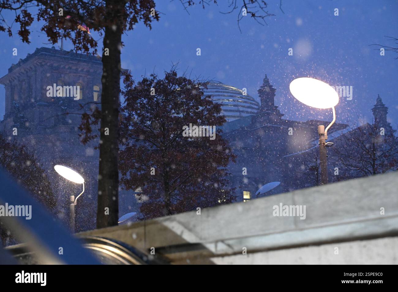 13 February 2025, Berlin: Snow falls in front of the Reichstag building ...