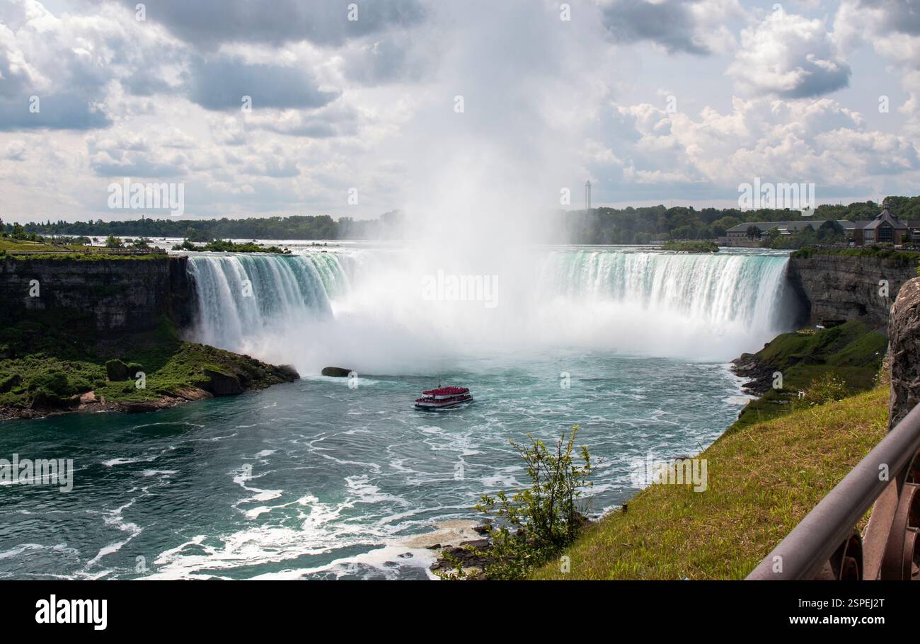 Powerful waterfalls flow into vibrant waters as a boat navigates the ...