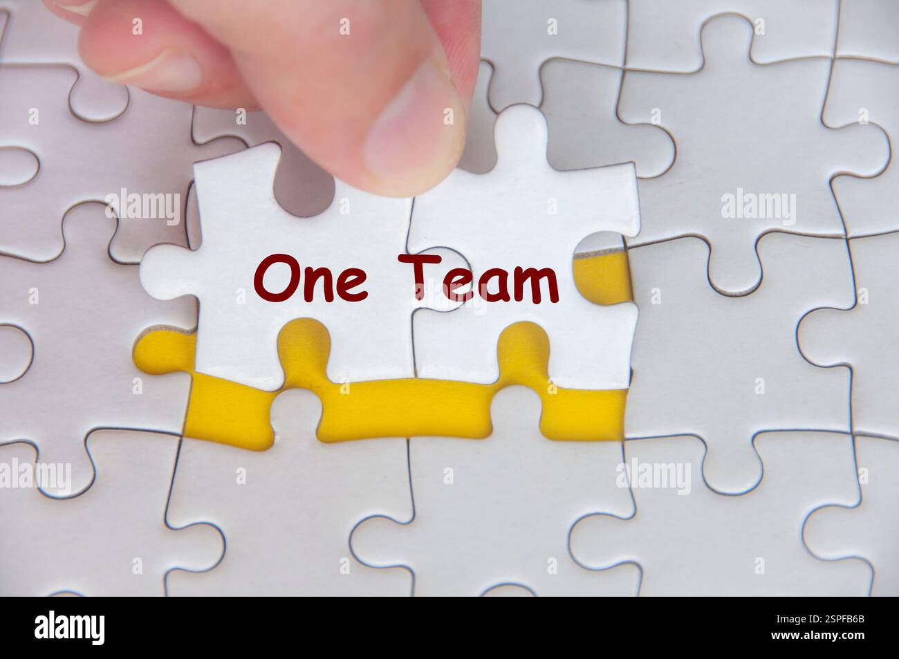 Hand holding One Team text on separated jigsaw puzzle. One team and ...