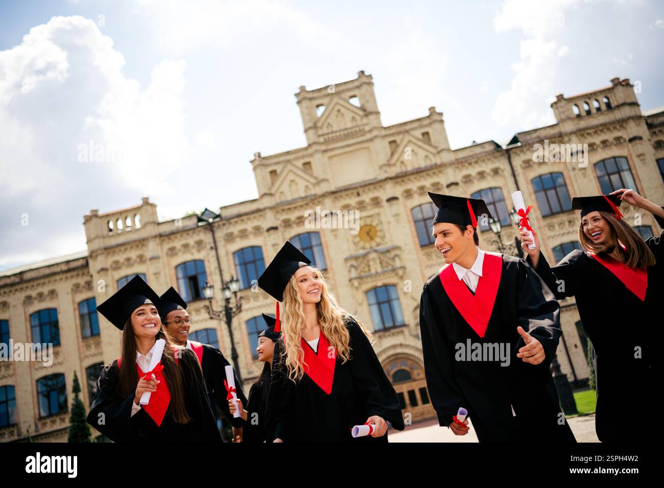 Joyful students celebrating graduation day outside university campus in ...