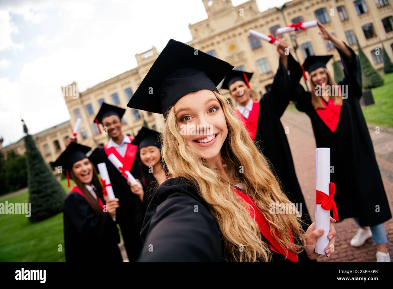 Joyful students celebrating graduation day outdoors on a sunny campus ...