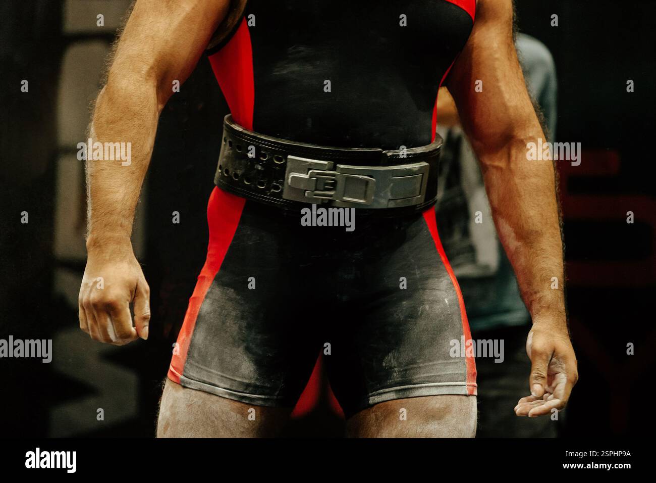 athlete in red and black singlet with weightlifting belt and spread ...