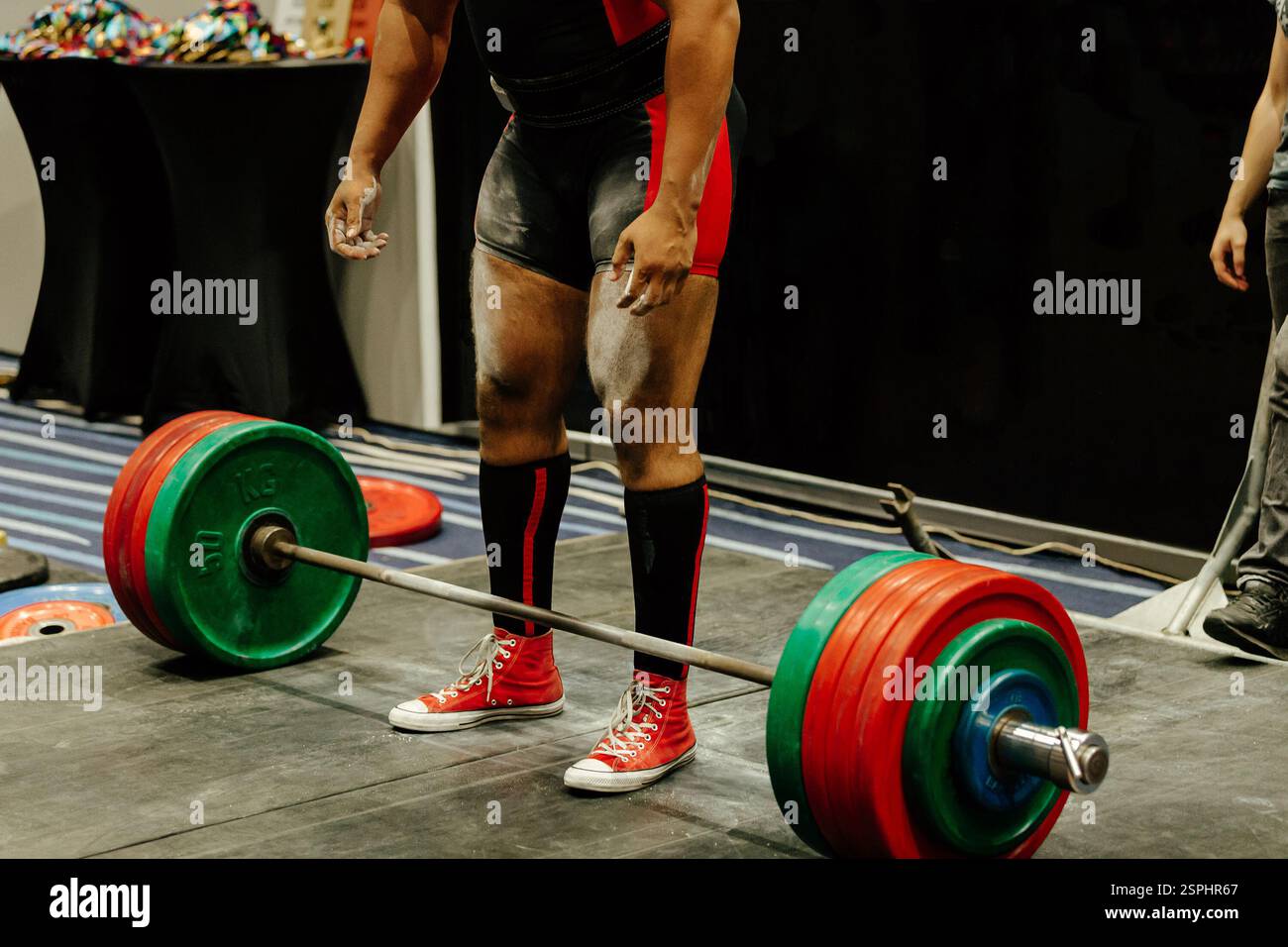 powerlifter stands in front heavy barbell and getting ready for ...