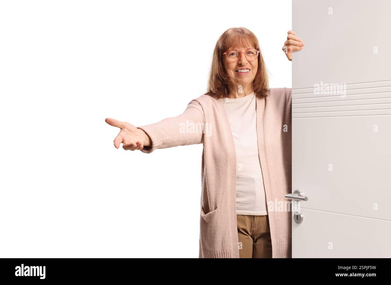 Excited mature woman behind a door gesturing welcome isolated on white ...