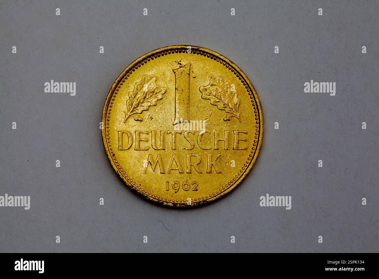 A close-up shows a gold-colored 1962 one Deutsche Mark coin. The coin ...