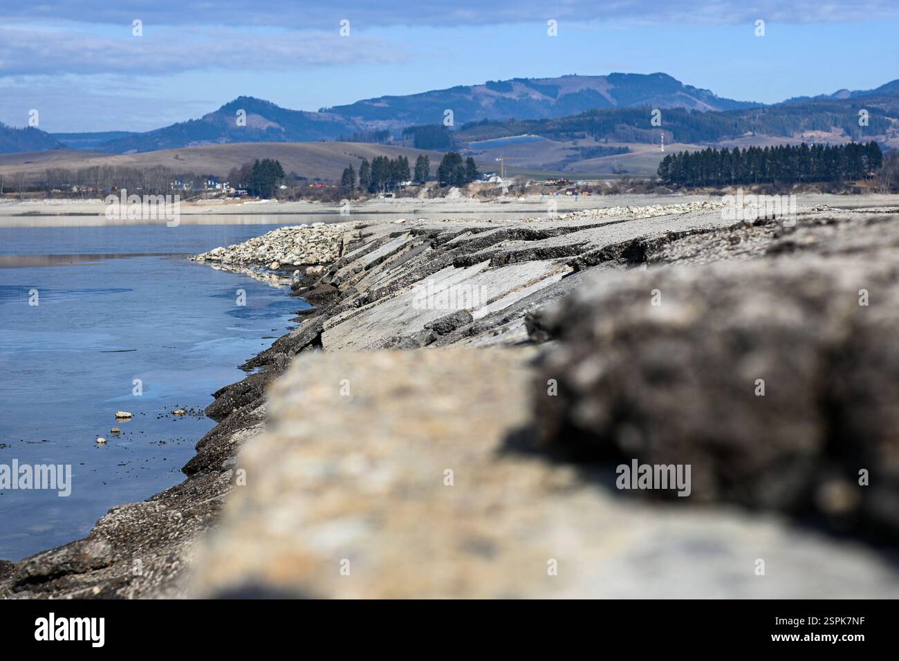 Cracked concrete slabs emerging from the dried lake bed with low water ...