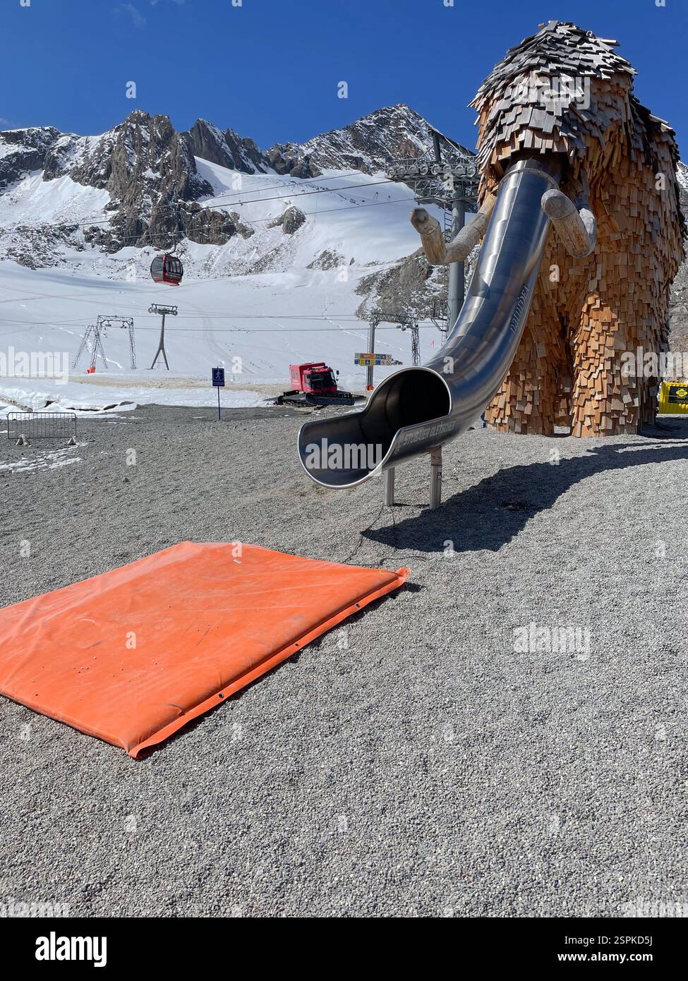 A large wooden mammoth sculpture with a metal slide as its trunk is ...