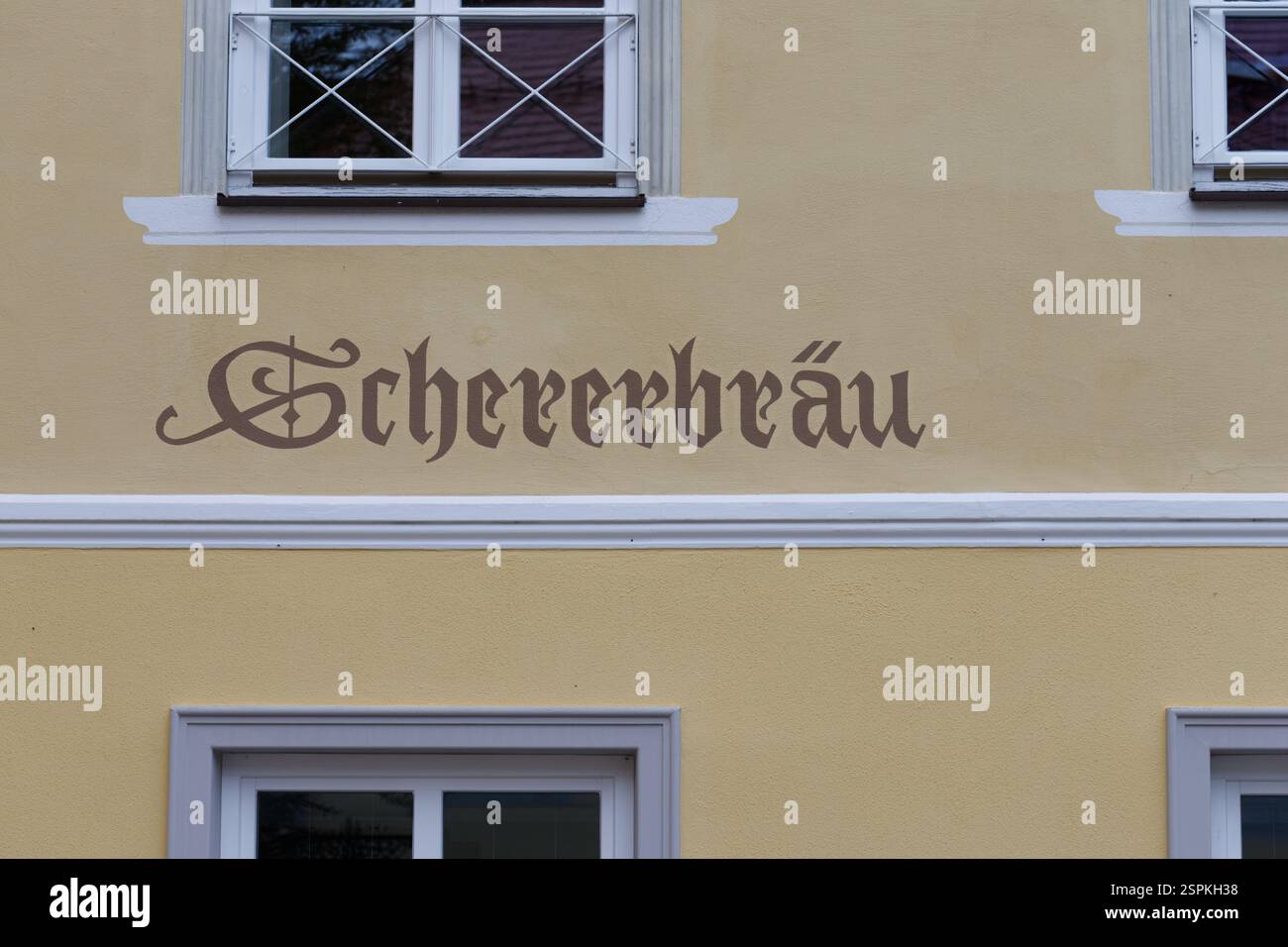 A tan building facade features a brown, fraktur-style lettering ...