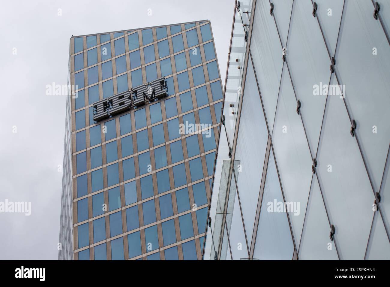 Two modern glass and metal buildings stand adjacent, one with a gridded ...
