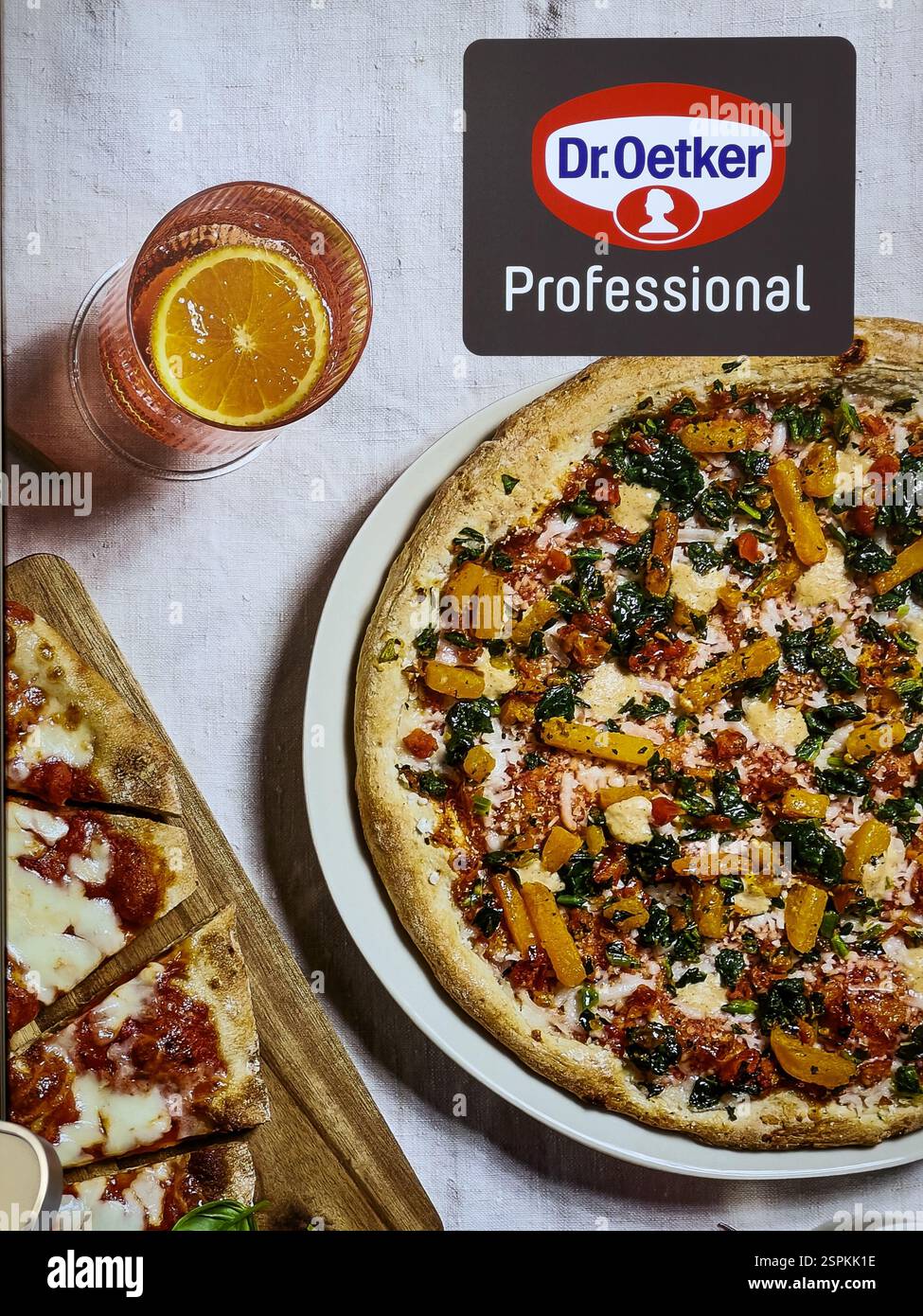 Overhead shot of two pizzas, a drink with orange slice, and a Dr ...