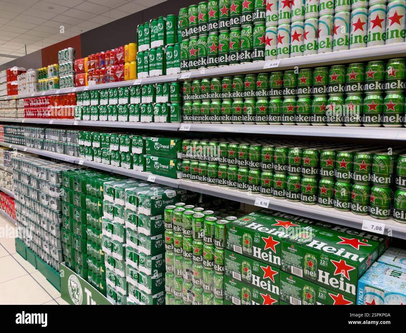A supermarket shelf displays various beer cans and packs, predominantly ...