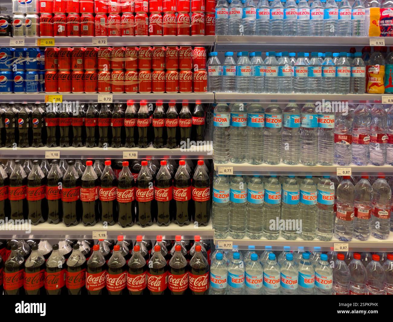A supermarket shelf displays rows of Coca-Cola products in cans and ...