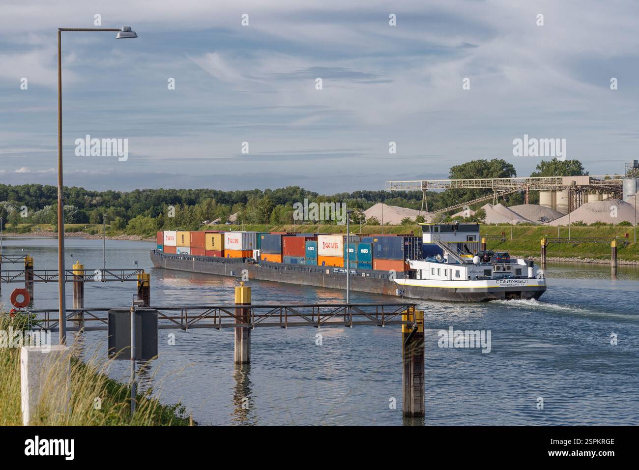 A barge carrying multiple shipping containers navigates a waterway. A ...