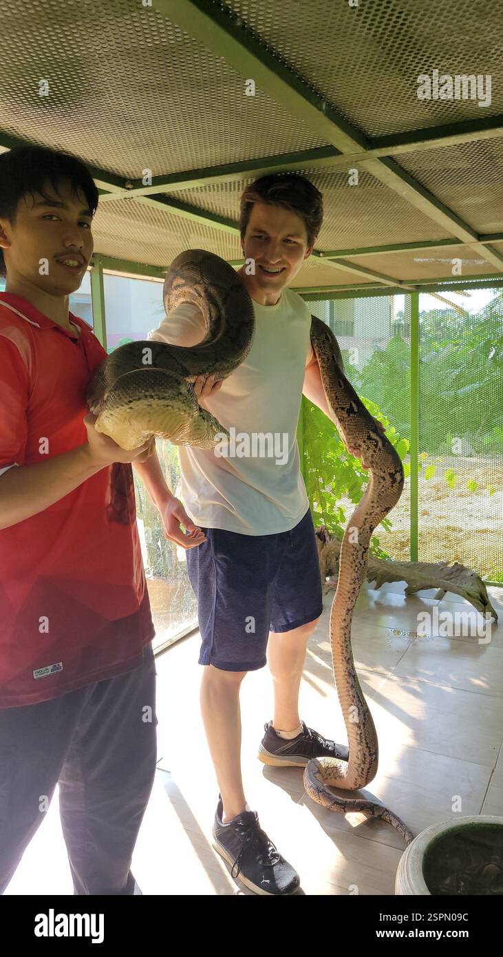 Tourists interact with snakes at a wildlife sanctuary in Thailand Stock ...