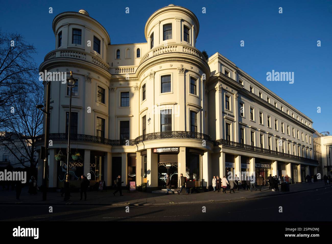 Pedestrians walk past the elegant, light beige West Strand building ...