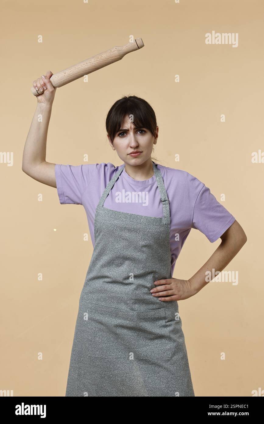 Angry woman with rolling pin on beige background Stock Photo - Alamy