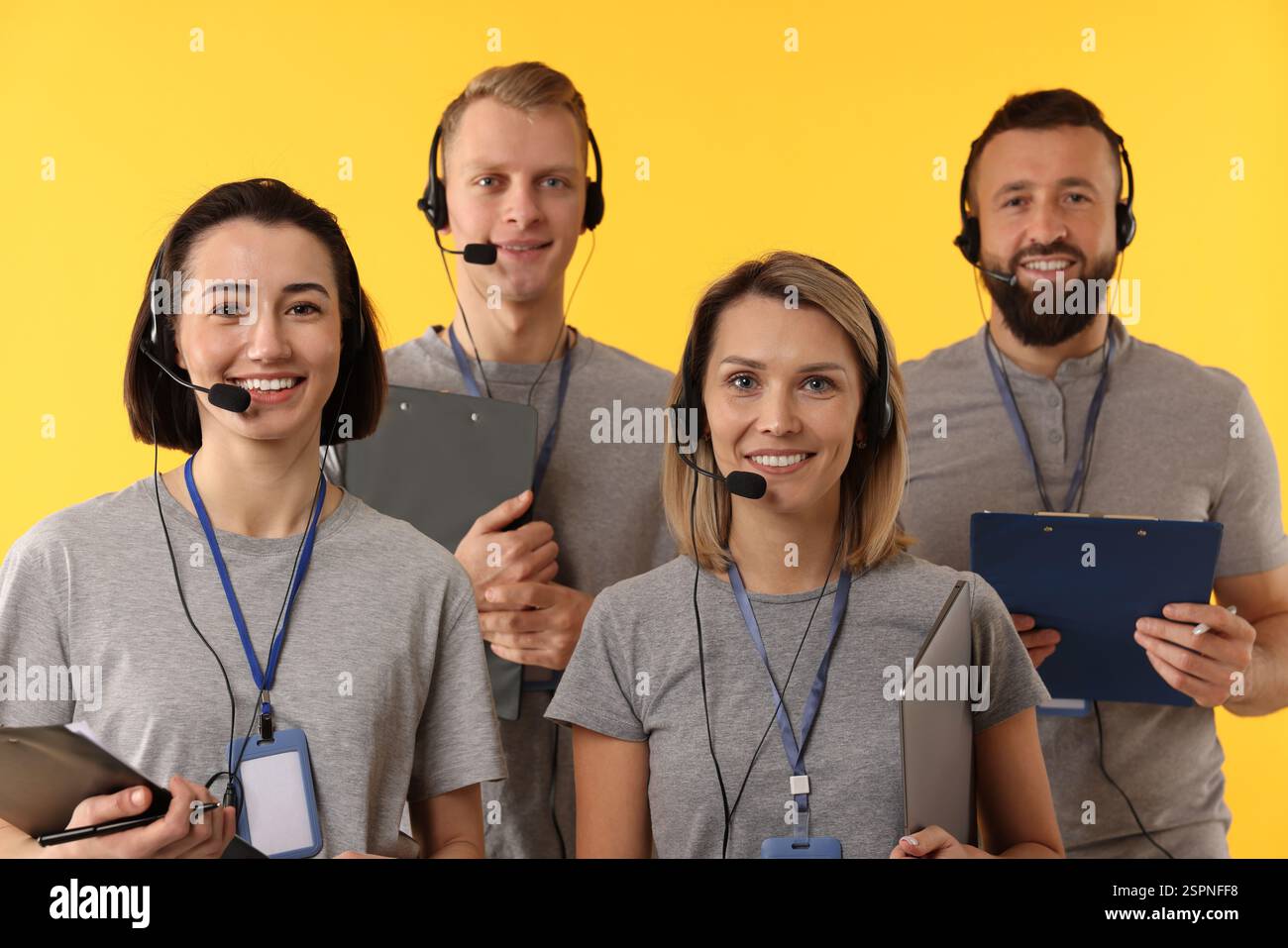 Technical support call center. Team of friendly operators on yellow ...