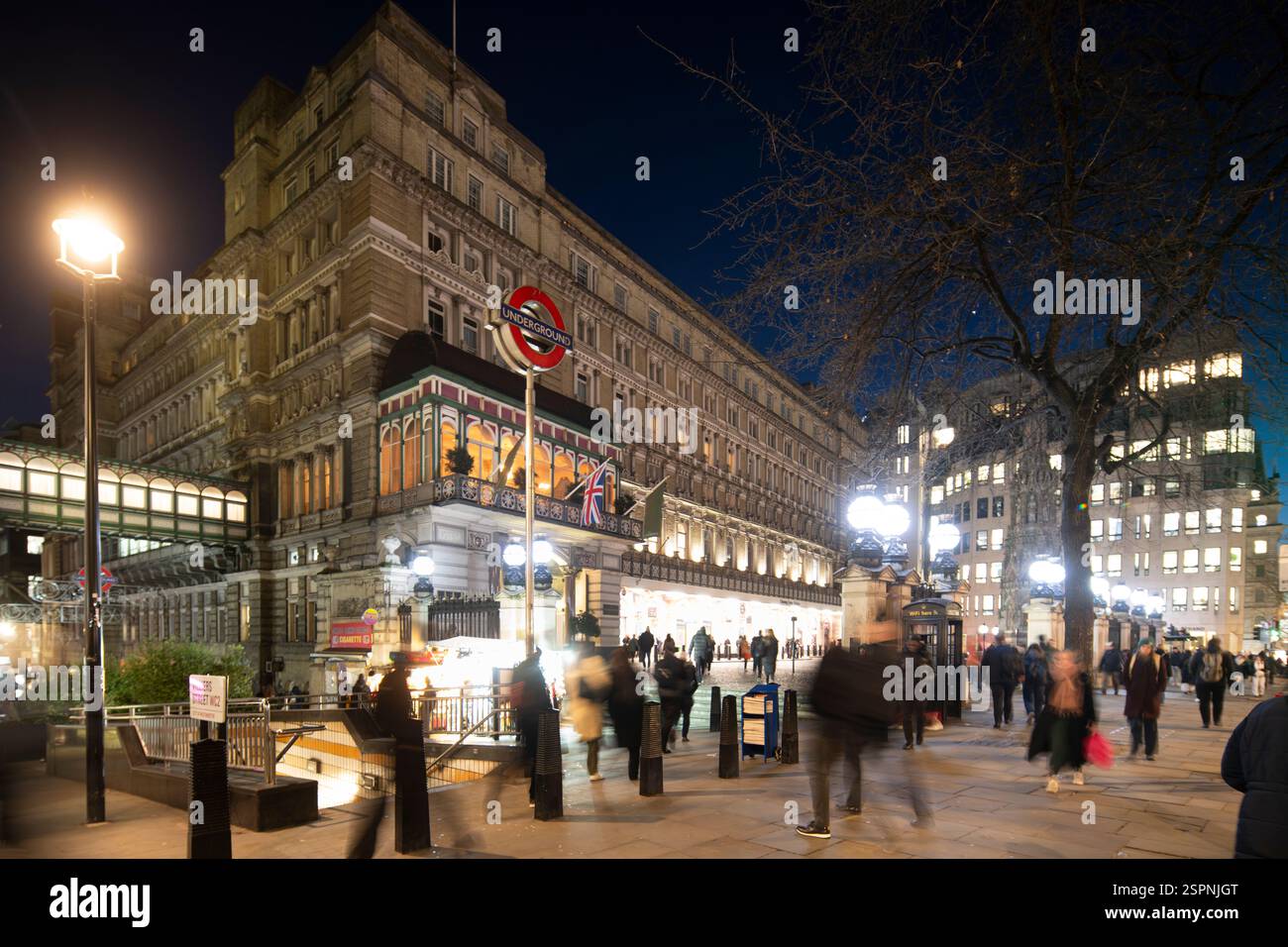 Night scene at London's Charing Cross Station. Pedestrians walk past ...