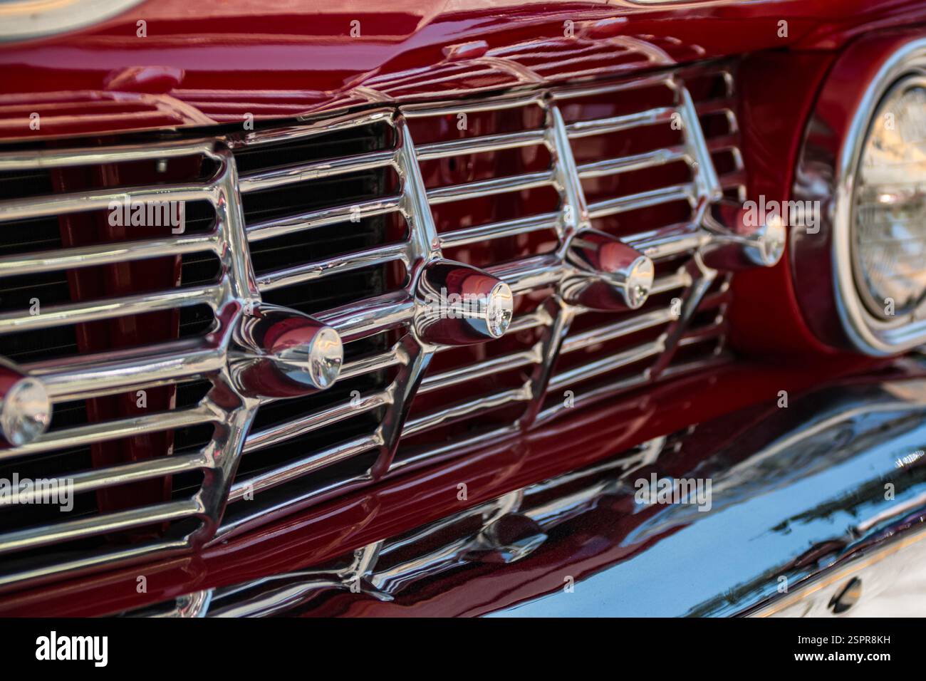 The unique bullet design of a chrome grille on a classic red 1959 ...