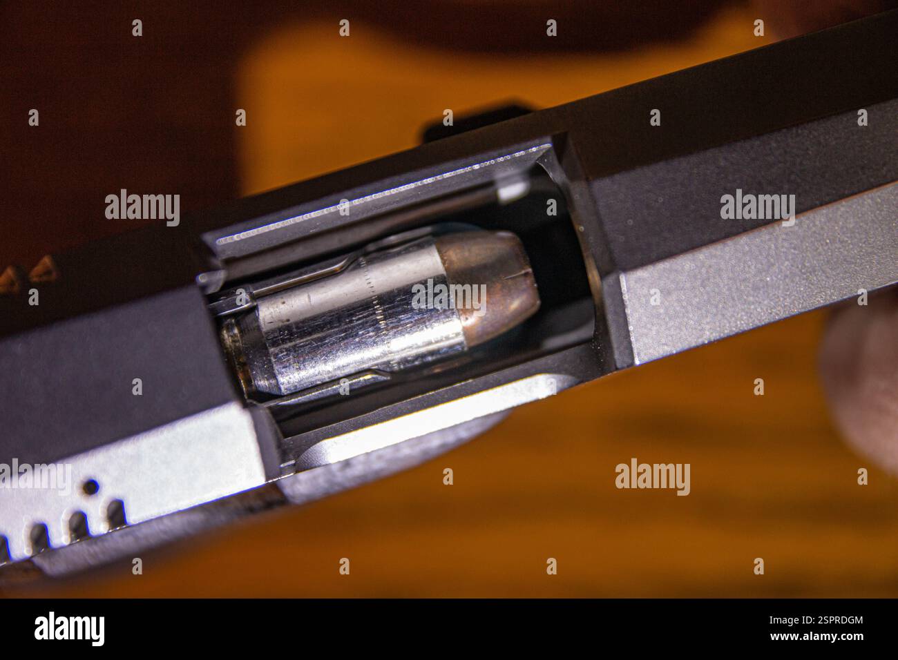 A .45 ACP caliber bullet is prepared to be chambered into a ...