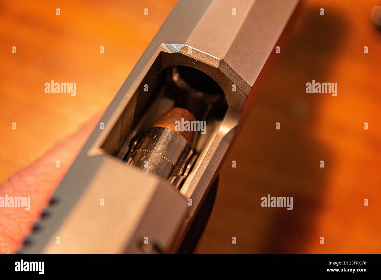 A .45 ACP caliber bullet is prepared to be chambered into a ...