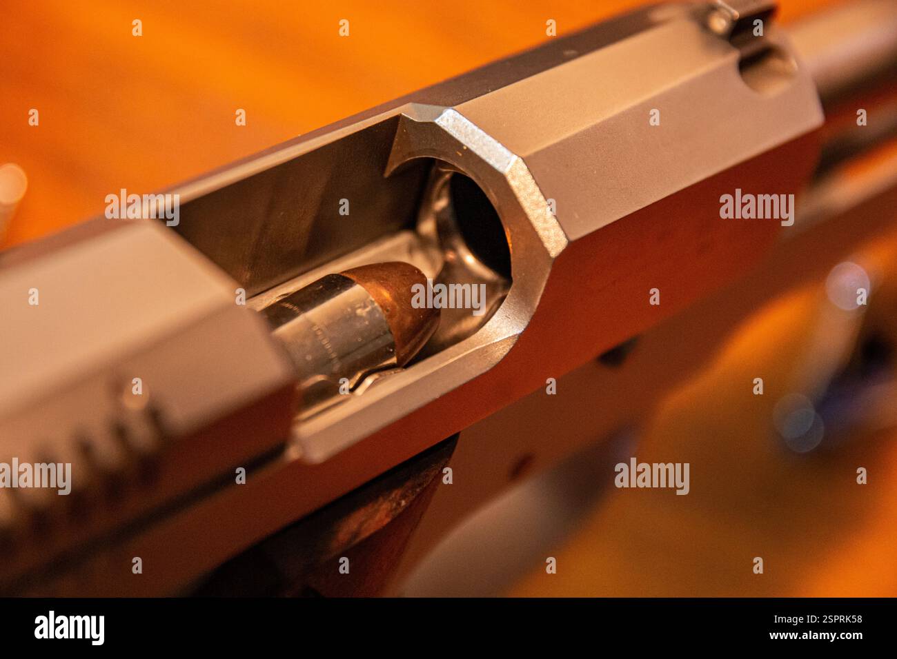 A .45 ACP caliber bullet is prepared to be chambered into a ...