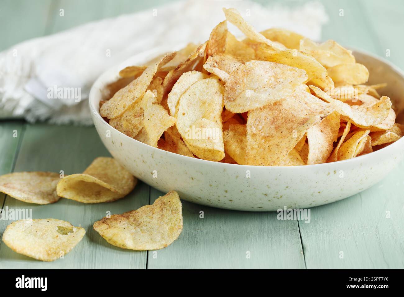 Crispy potato chips in a bowl over a bright table. Selective focus with ...