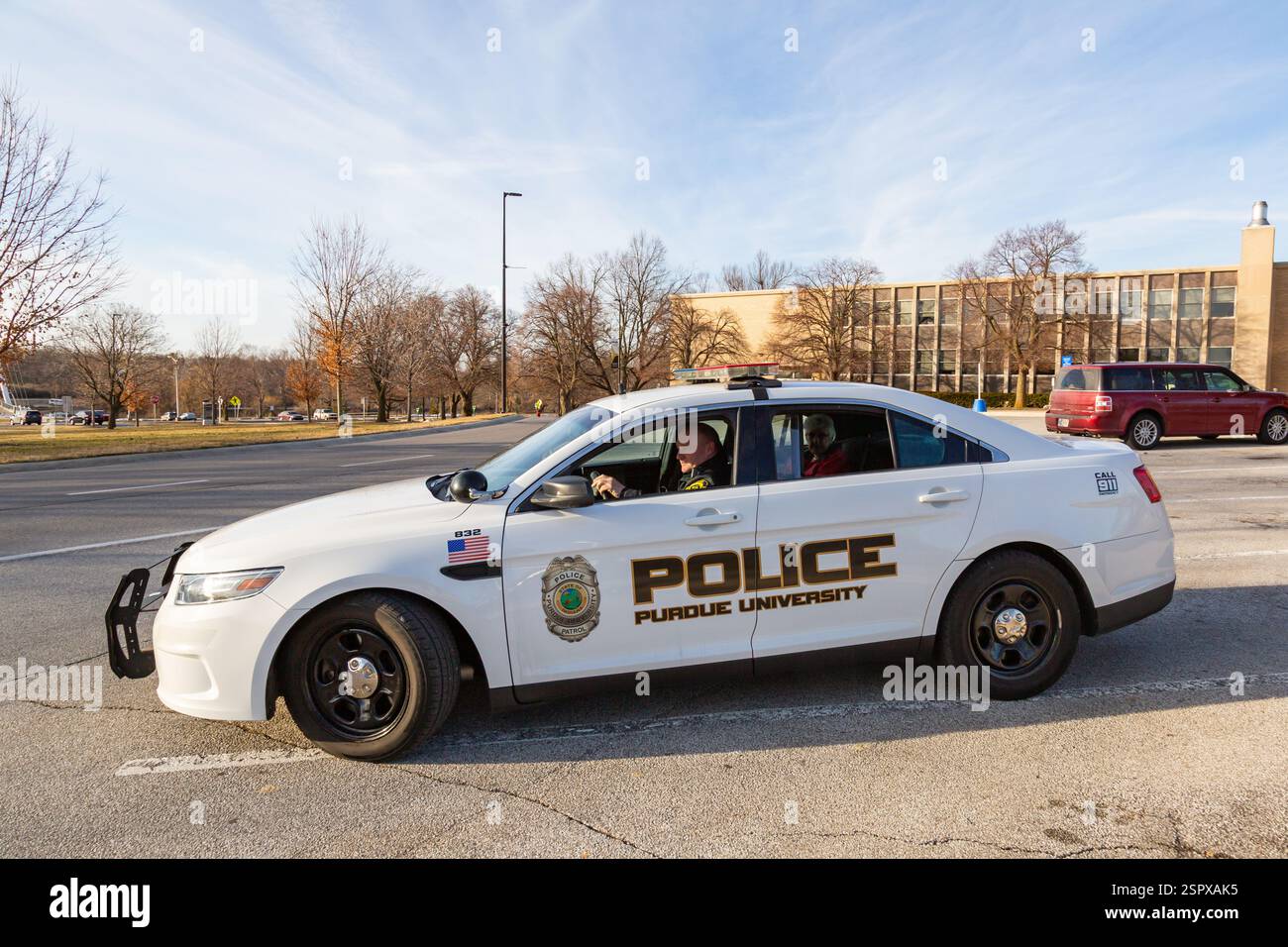 An elderly woman sits in the back as a police officer drives a white ...
